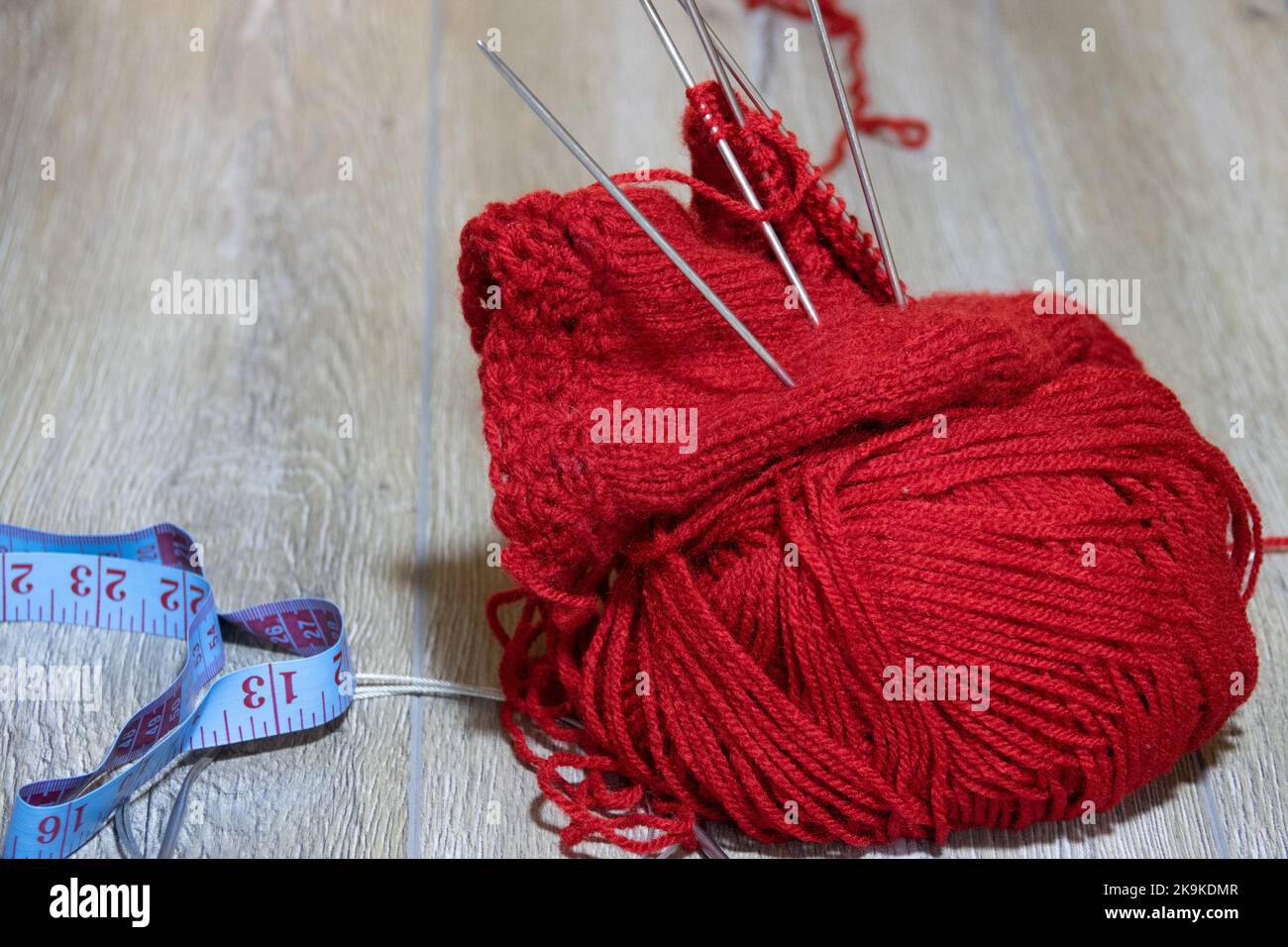 Sock in the process of knitting with needles and yarn of red color on a ...