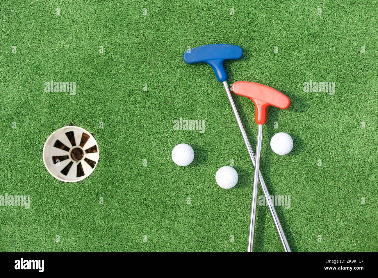 Assorted miniature golf putters and balls askew on synthetic grass ...