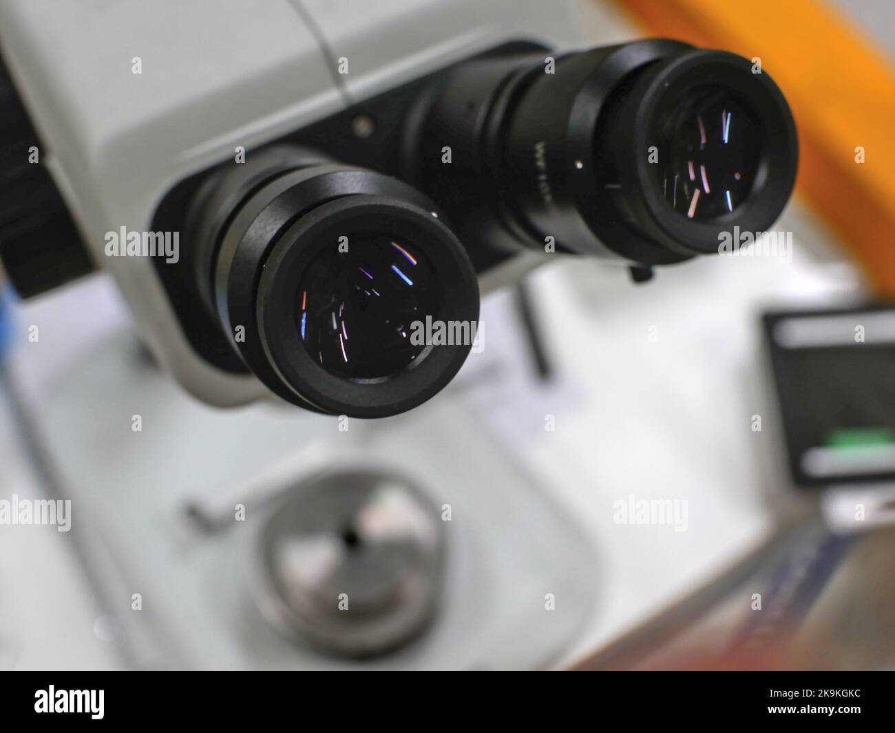 Close-up on optics of a binocular microscope, its base is in blurred ...