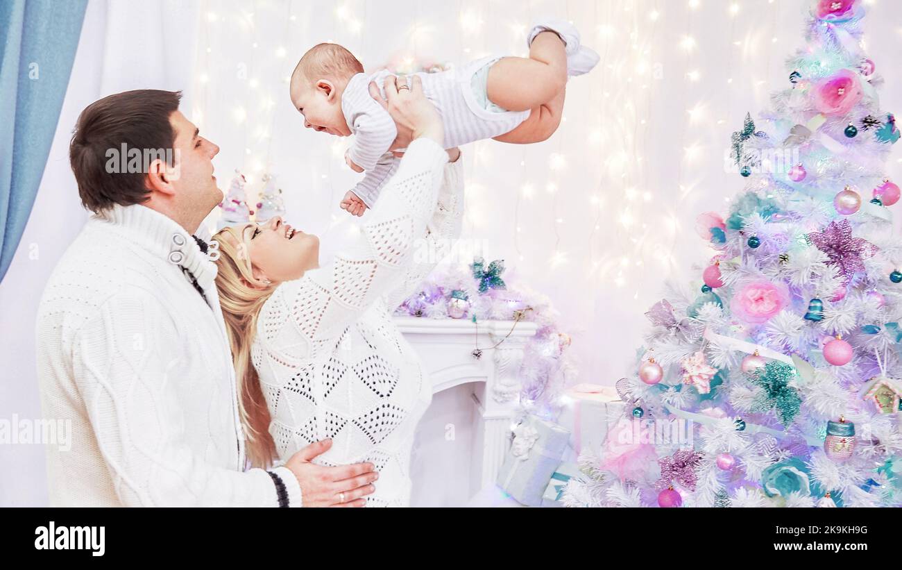 loving parents with play with their baby standing in the festive living ...