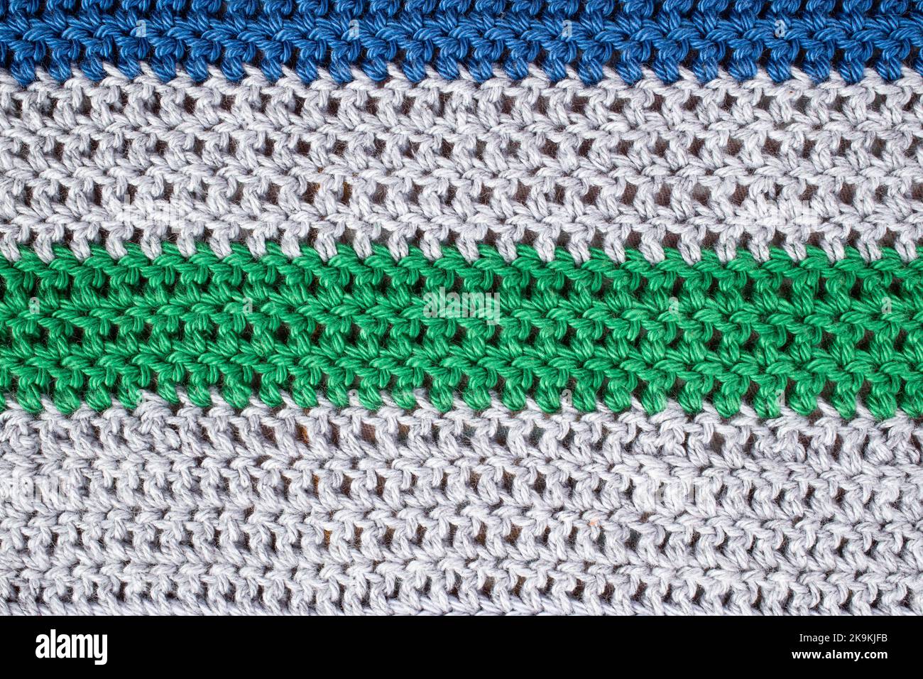Gray crochet pattern with blue and green horizontal lines. flat lay ...
