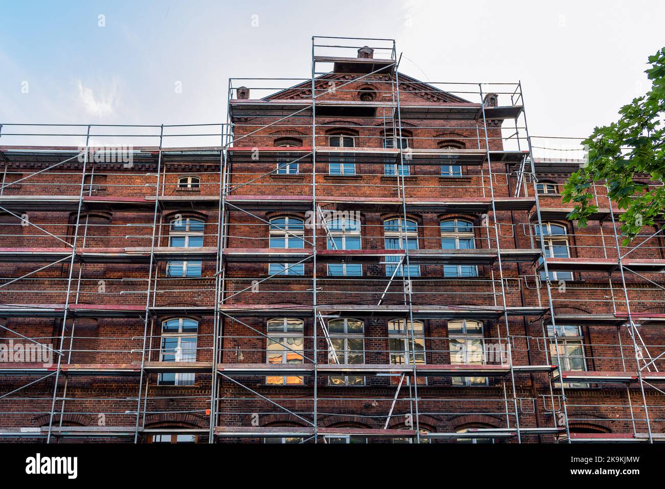 The scaffolding is laid out at the facade of the building made of brick ...