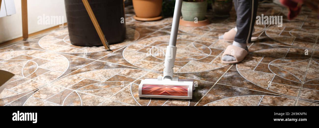 Woman housewife cleaning floor with cordless vacuum cleaner closeup ...