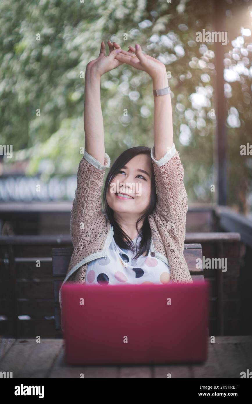 Happy asian woman raise arm up from body and muscles while working with ...