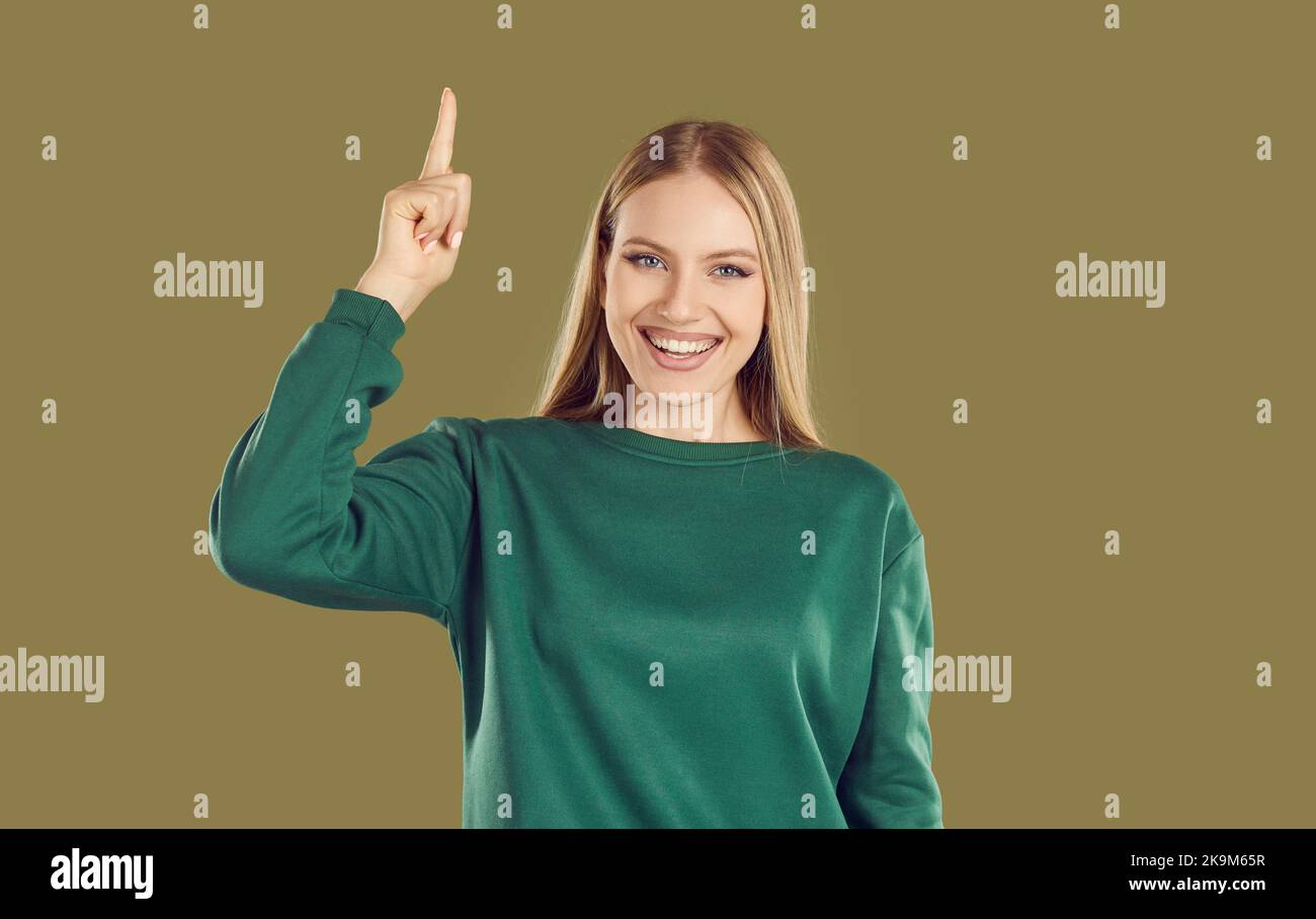 Blondy laughing friendly woman is pointing finger up on copyspace on ...