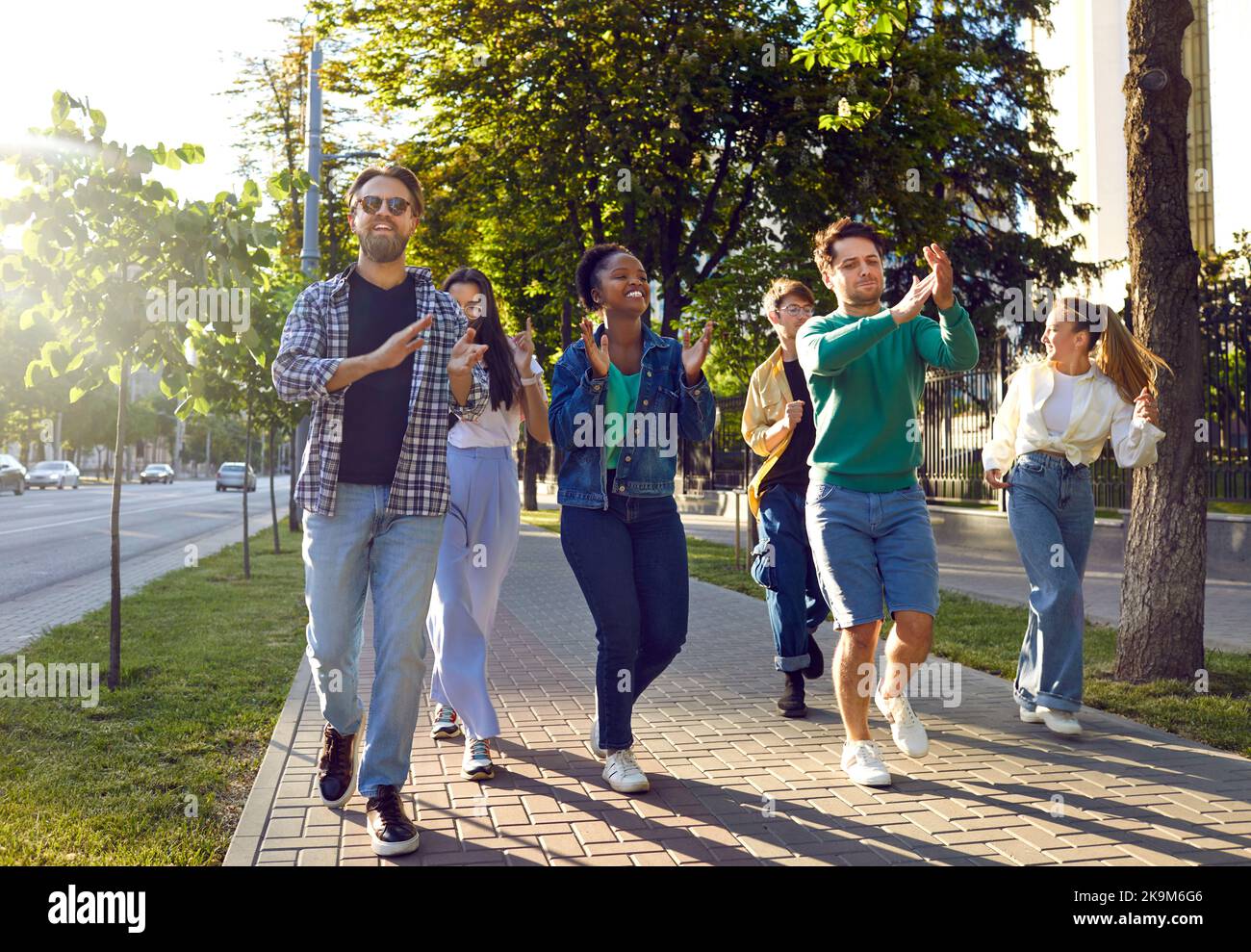 Cheerful energetic friends on warm summer evening walking streets of ...