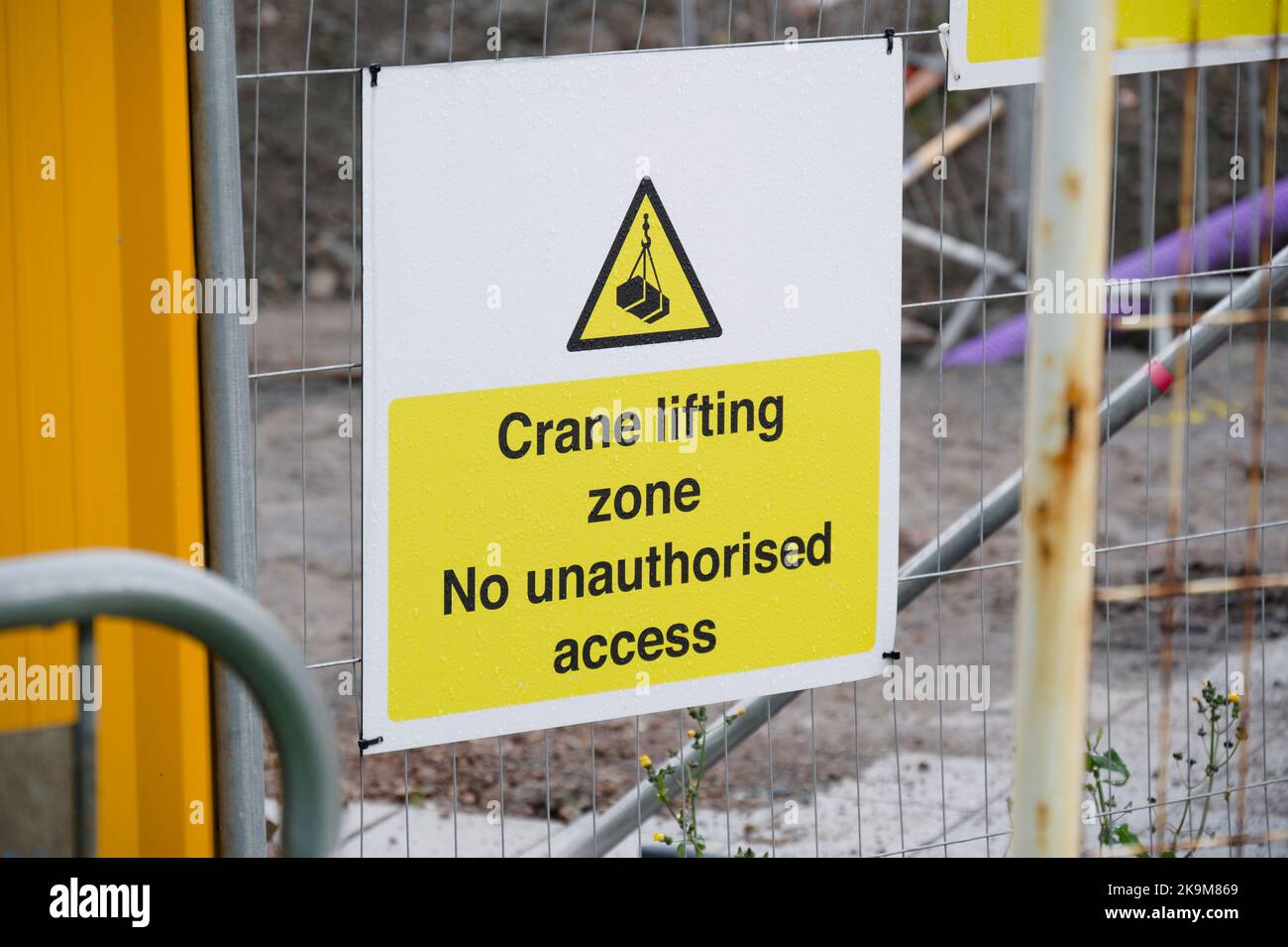 Crane lifting safety sign on construction site fence Stock Photo - Alamy