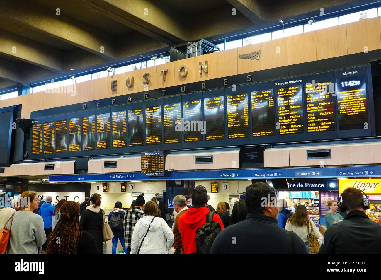 Crowd of people, standing in front of the departures board, waiting for ...