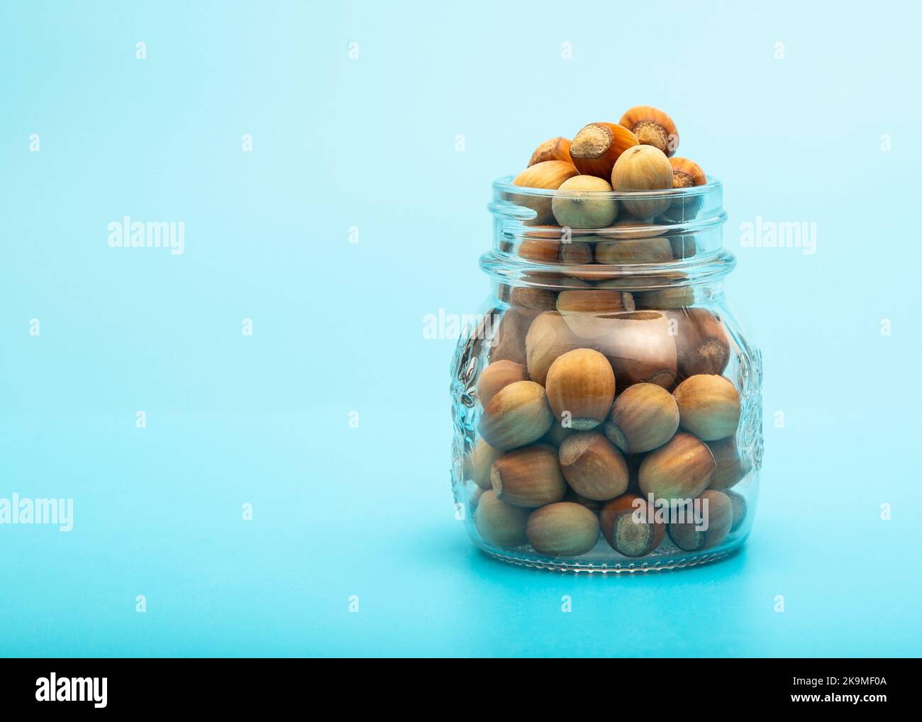 Hazelnut in a jar. Lots of hazelnuts. Bank with nuts on a blue ...