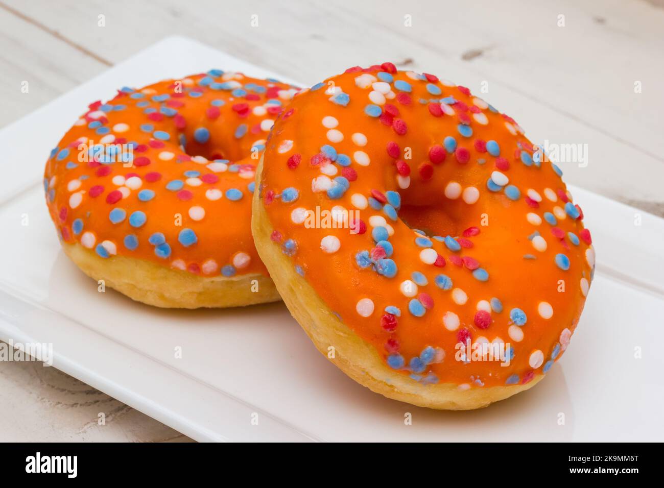 Two orange donuts with sprinkles in the colors of the dutch flag for ...