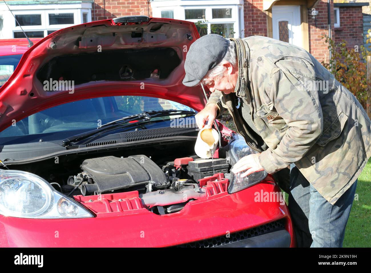 Man topping up the water levels in his radiator and screen wash of his ...
