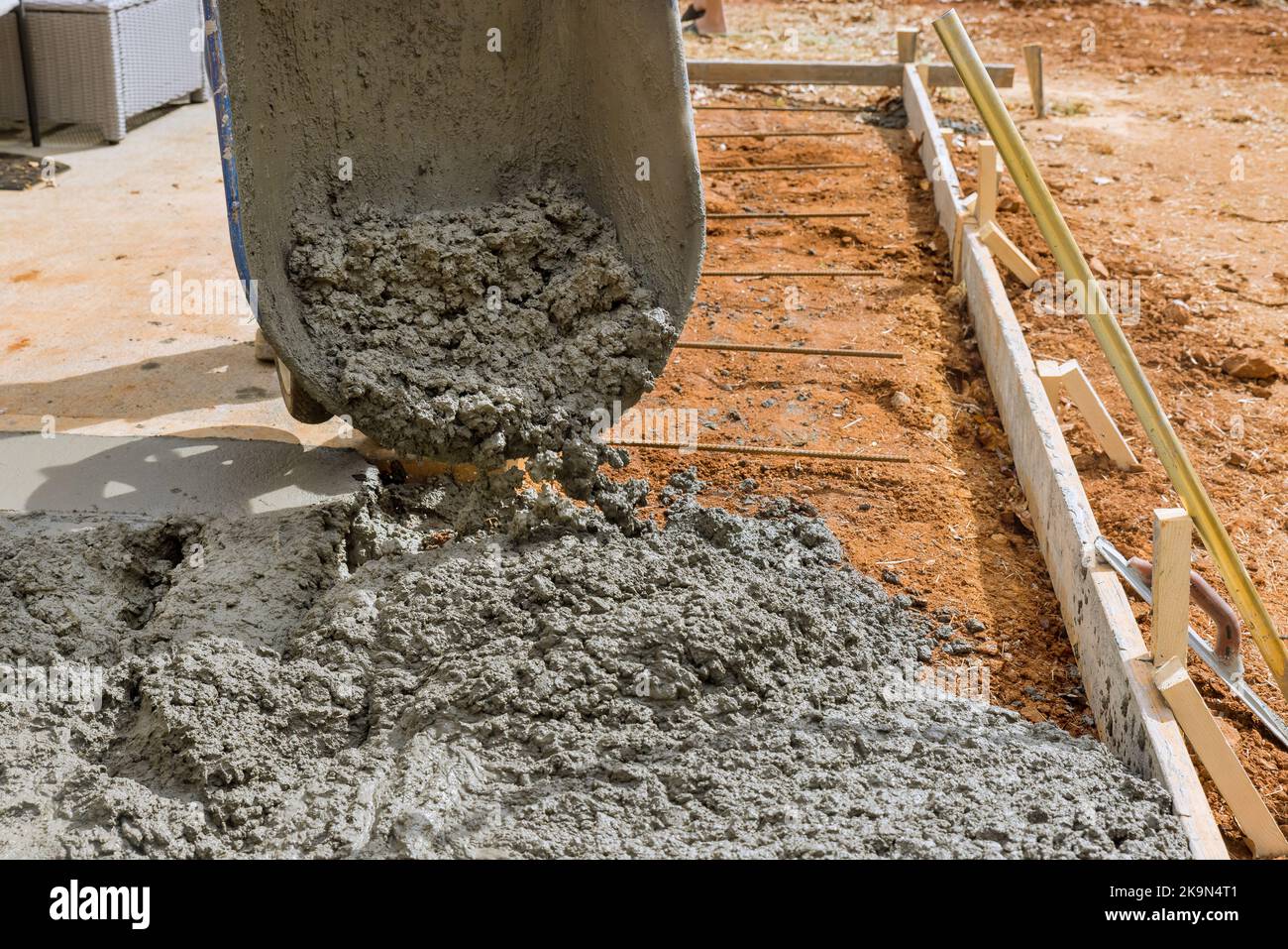 Construction contractors pouring wet concrete while paving driveway as ...