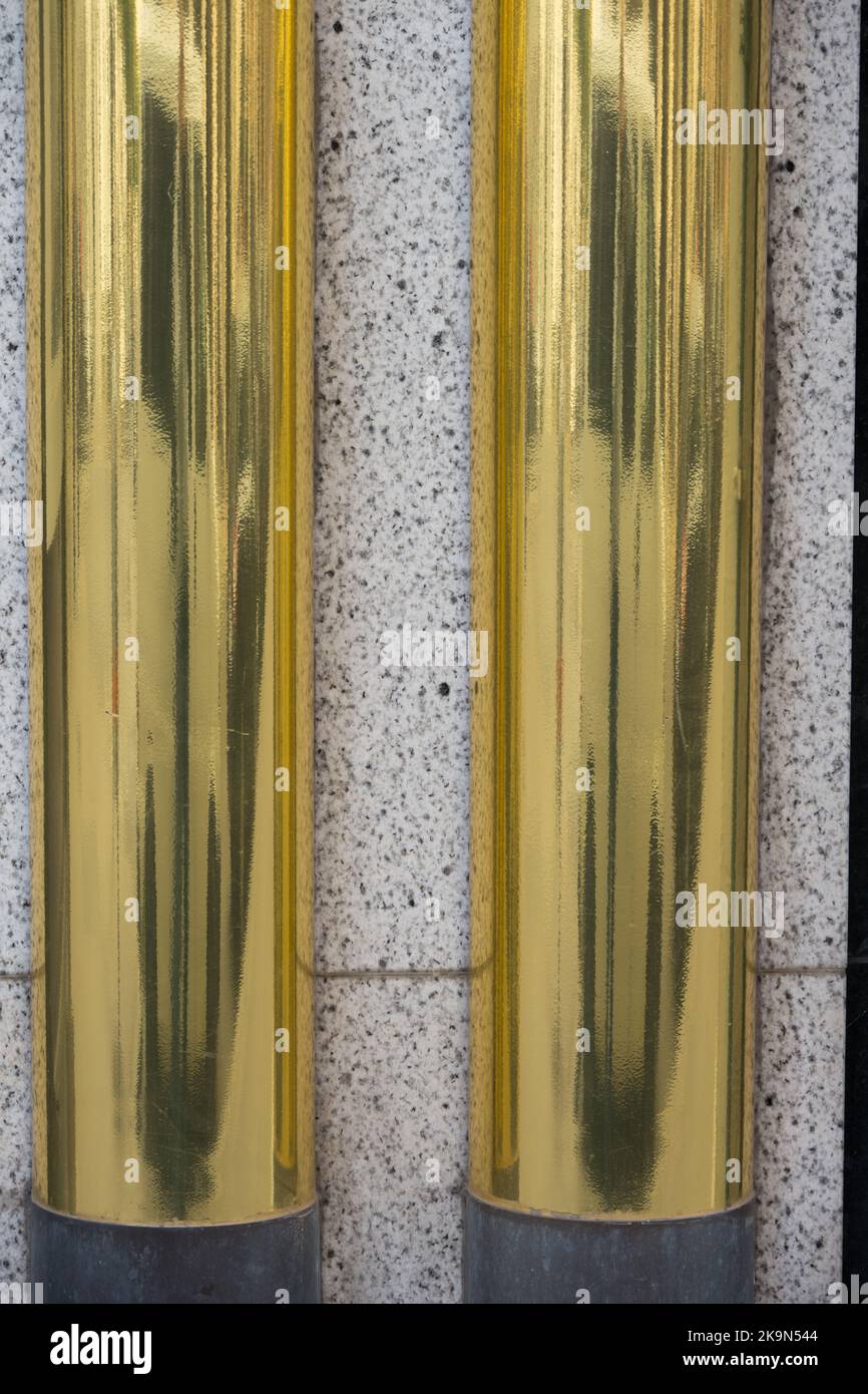 Close-up of noble house facade with two golden brass semicircular columns mounted on granite ...