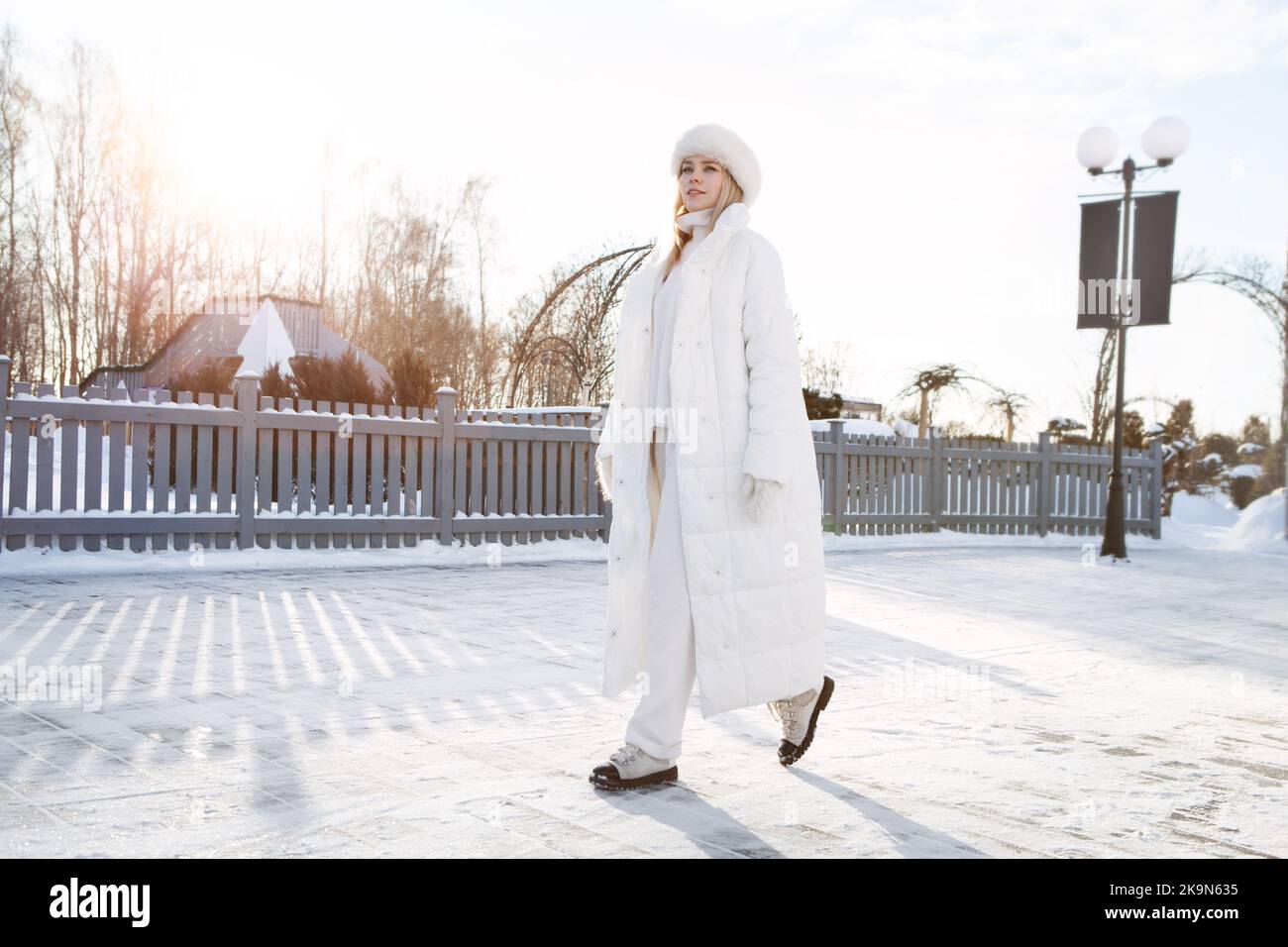 Beautiful young woman walking outdoors on winter street in warm white ...