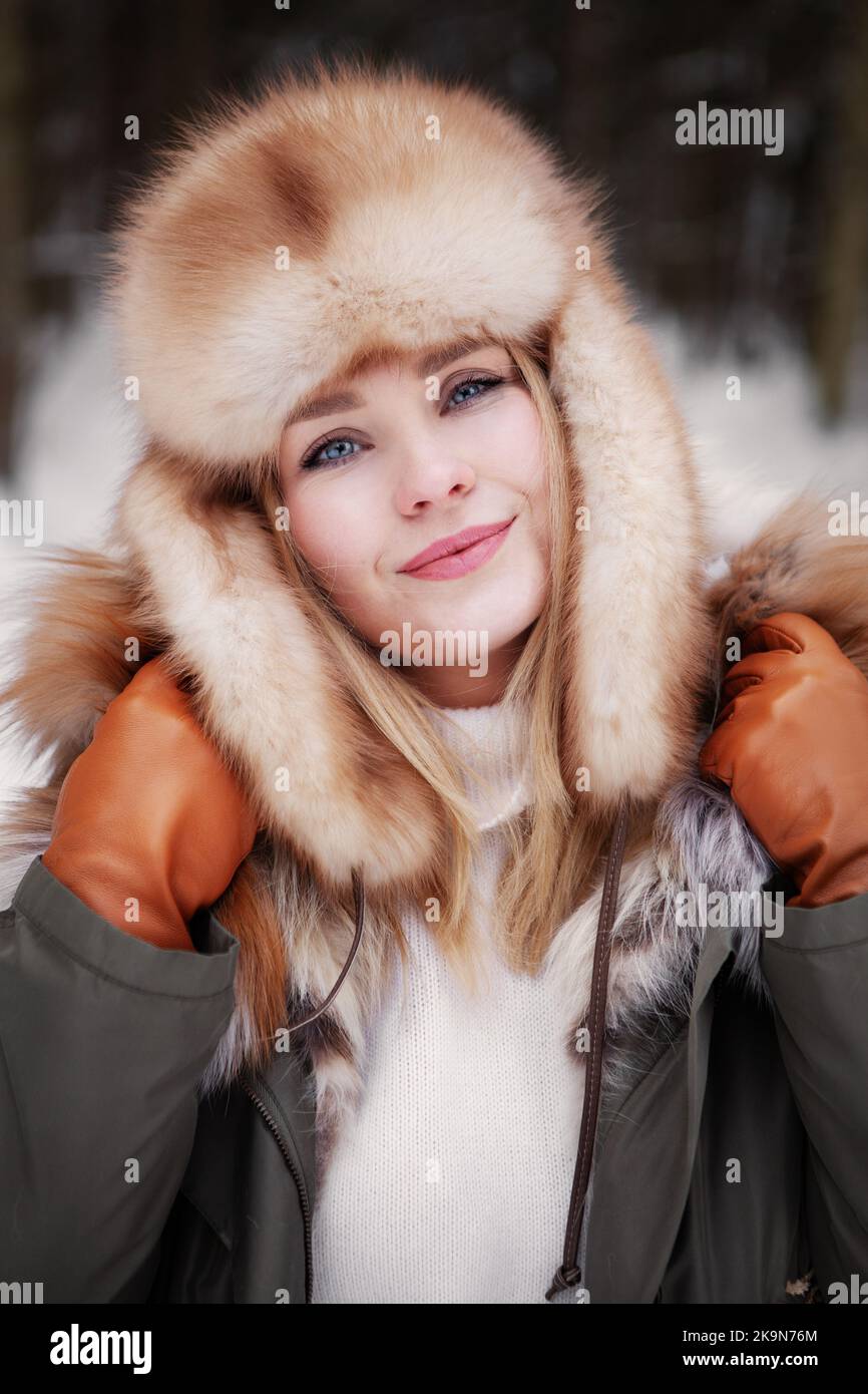 Woman face and chest portrait close up in jacket, ear flaps fur hat and ...