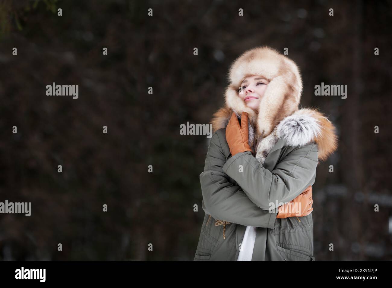 Woman wrap and hug herself on dark background, wearing winter jacket ...
