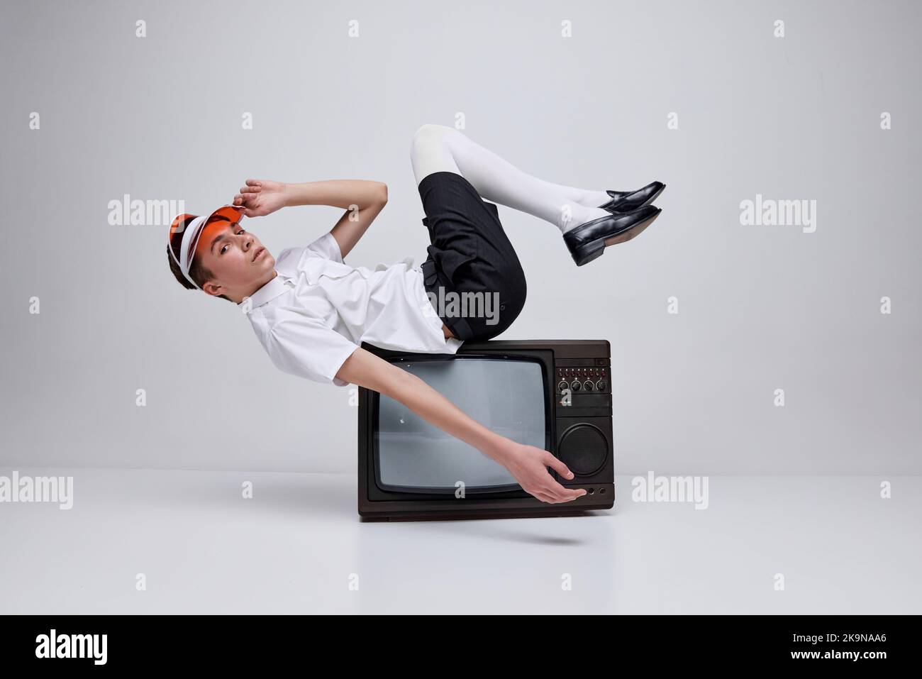Portrait of stylish young man, boy posing on retro TV isolated over ...