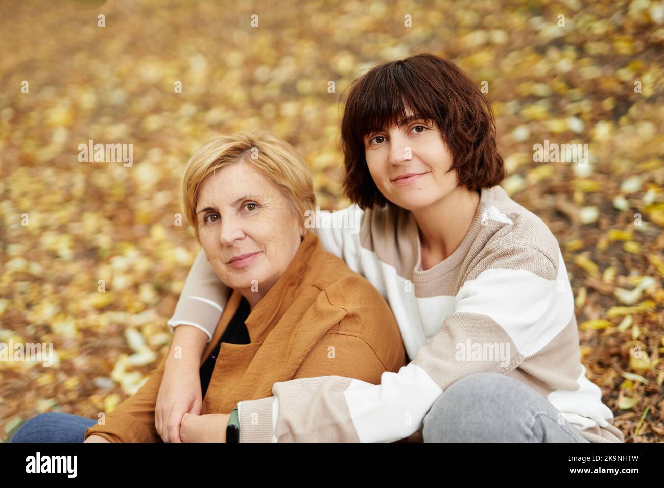 Caucasian mother and her daughter sitting in autumn park. Portrait of ...