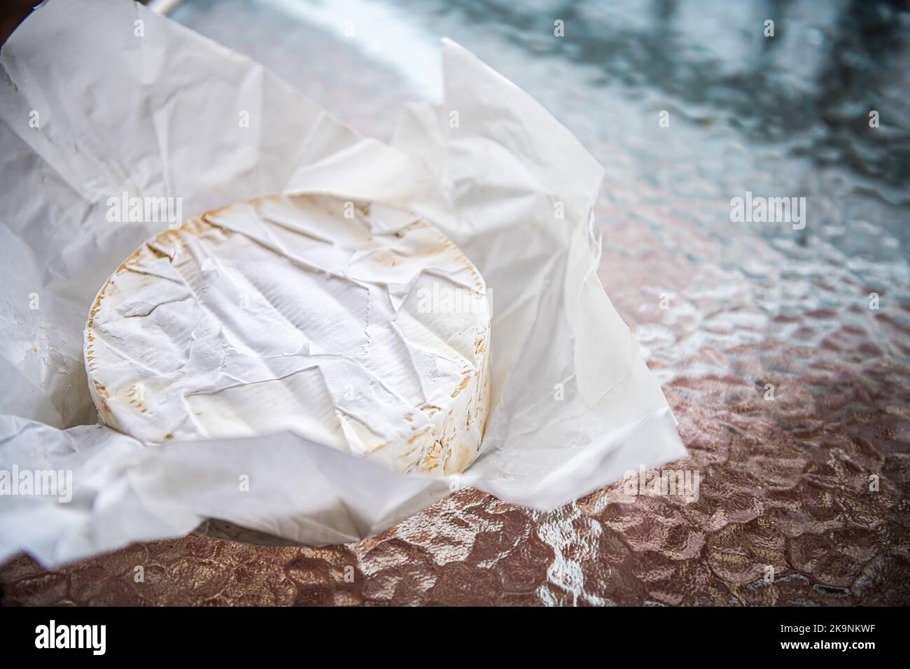 French soft brie cheese wheel truckle, whole round shape in paper wrap ...