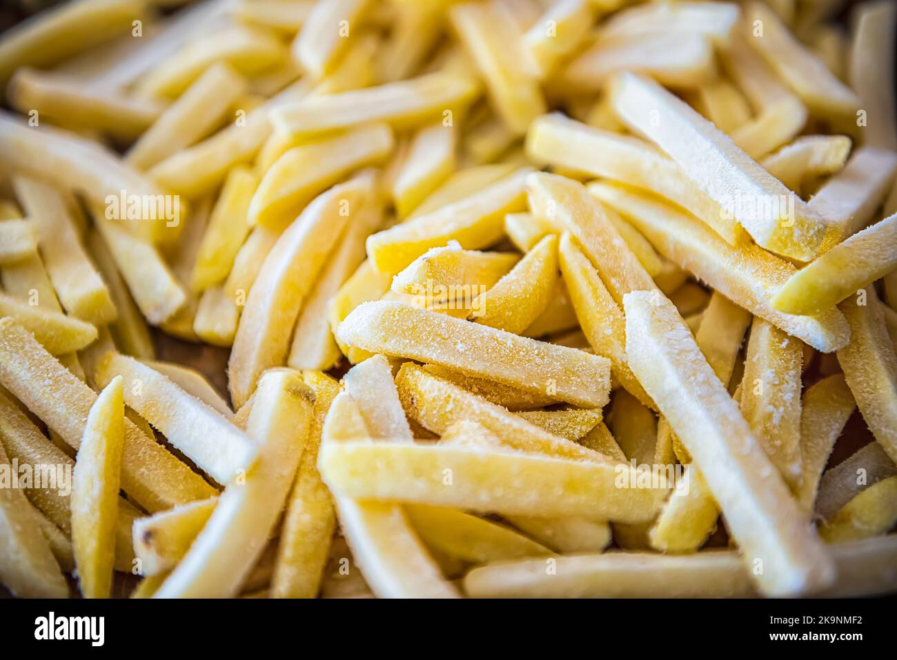 Macro closeup of frozen uncooked raw straight cut salty french fries ...