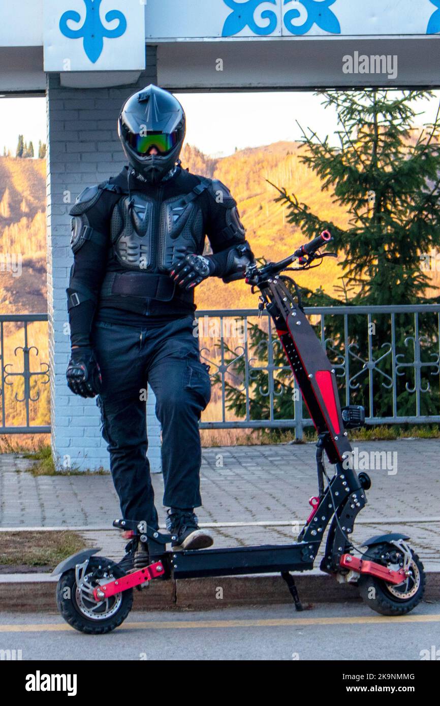 a man in full protection with a sports electric scooter Stock Photo - Alamy