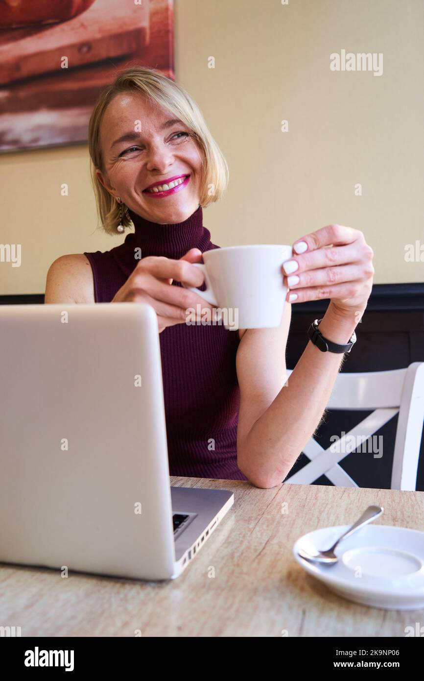 Vertical photo of a mid adult woman working from a cafeteria and ...
