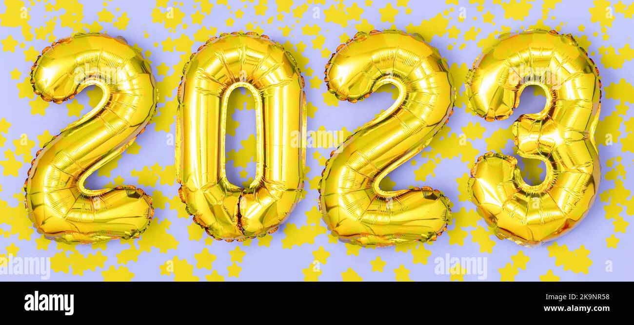 2023 golden foil balloons numbers, stars confetti, ribbons and bokeh. Top horizontal view copy ...