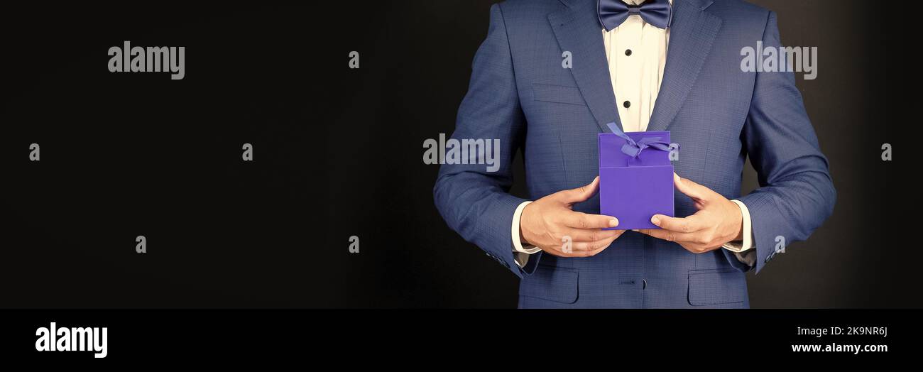 cropped man in tuxedo bow tie formalwear on black background with box ...