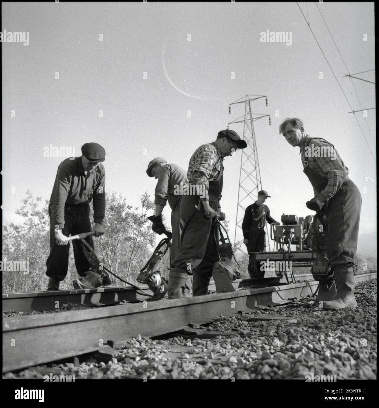 Track workers adjust the ballast under the tracks with vibrator skewers ...