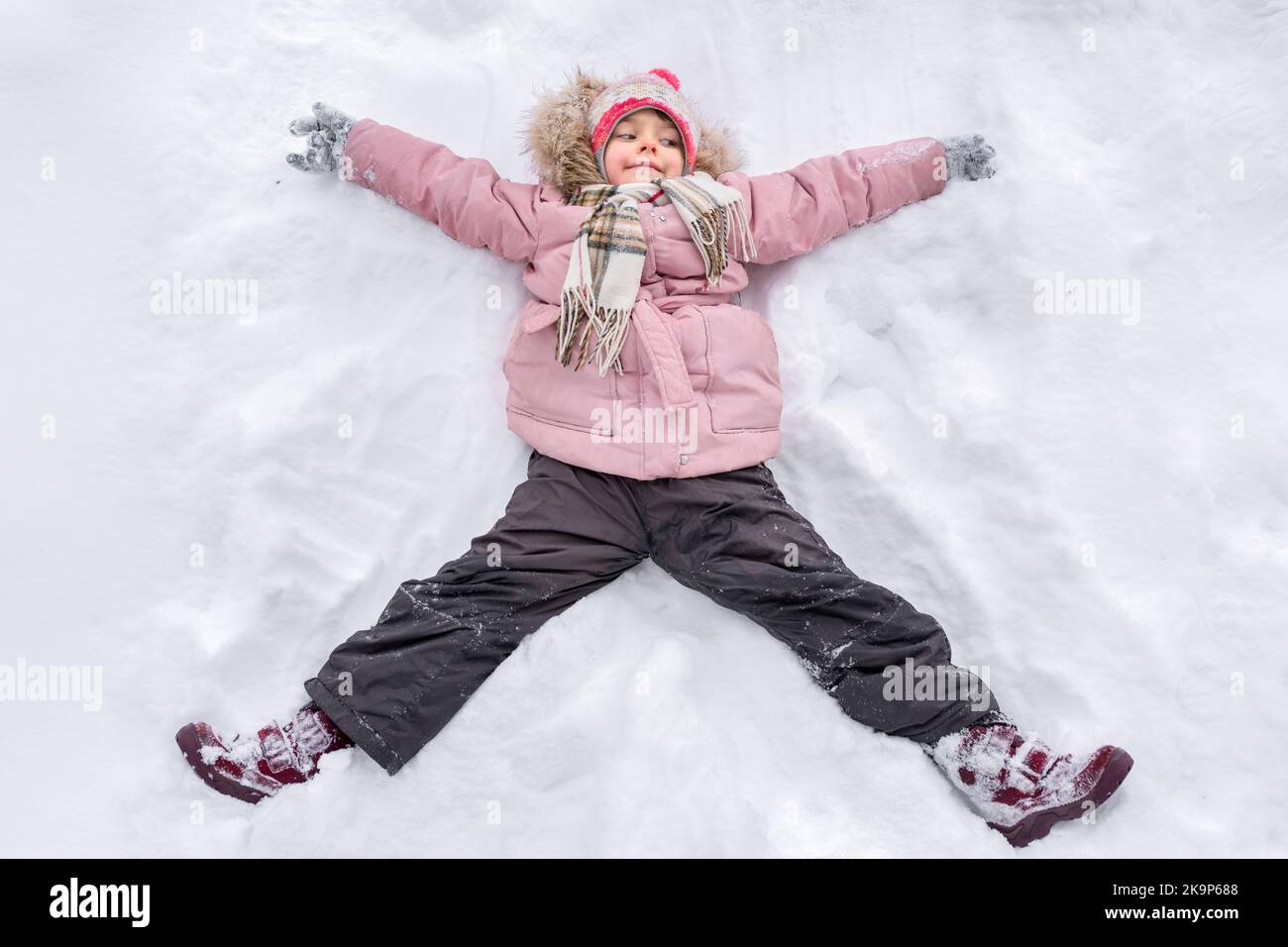 Little girl making snow angel outdoors in winter. Winter vacation and ...