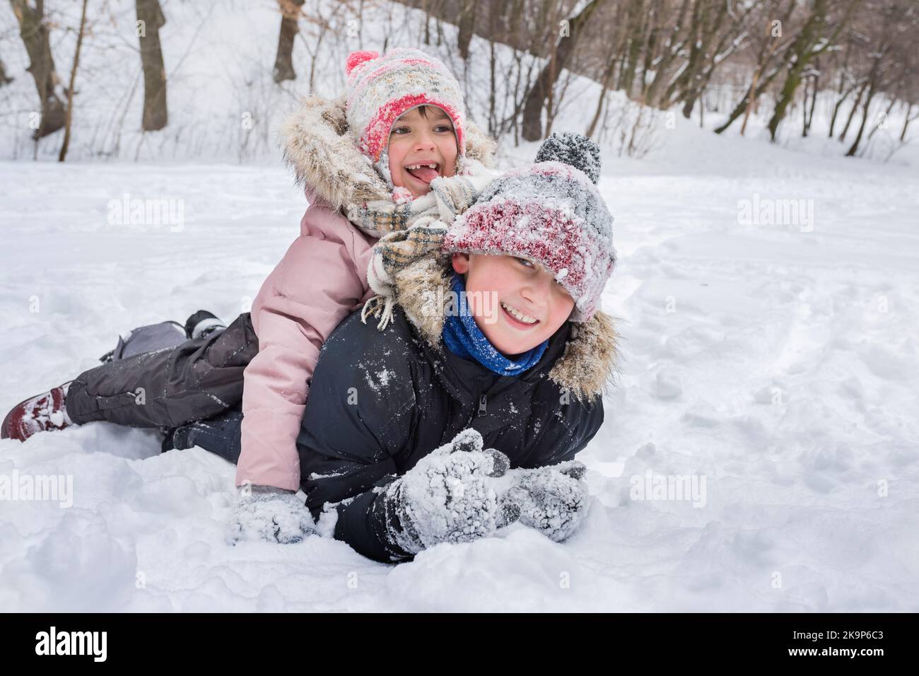 Happy children in winterwear laughing while playing in snowdrift ...