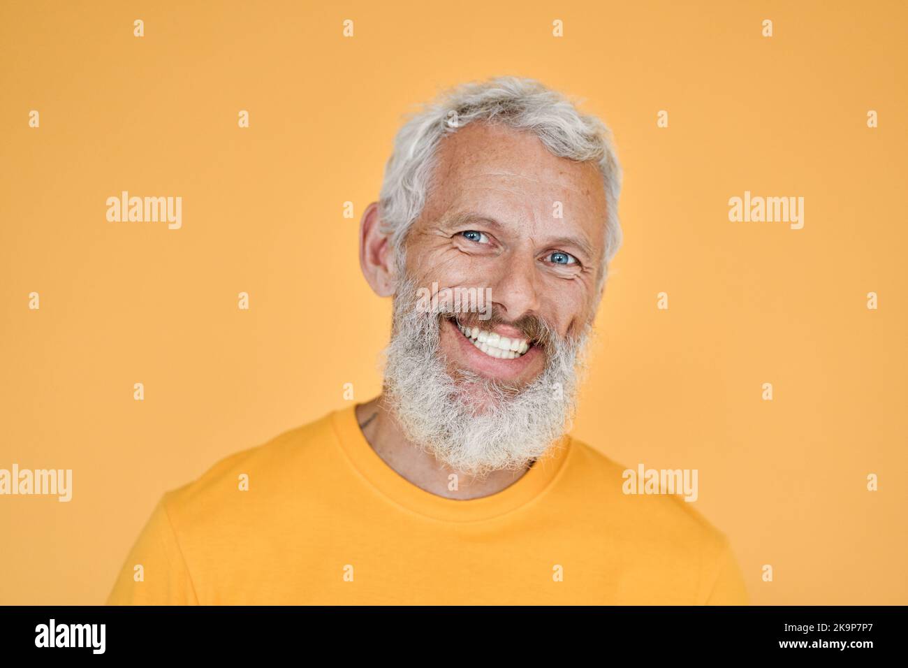 Smiling older bearded man isolated on yellow background, headshot ...
