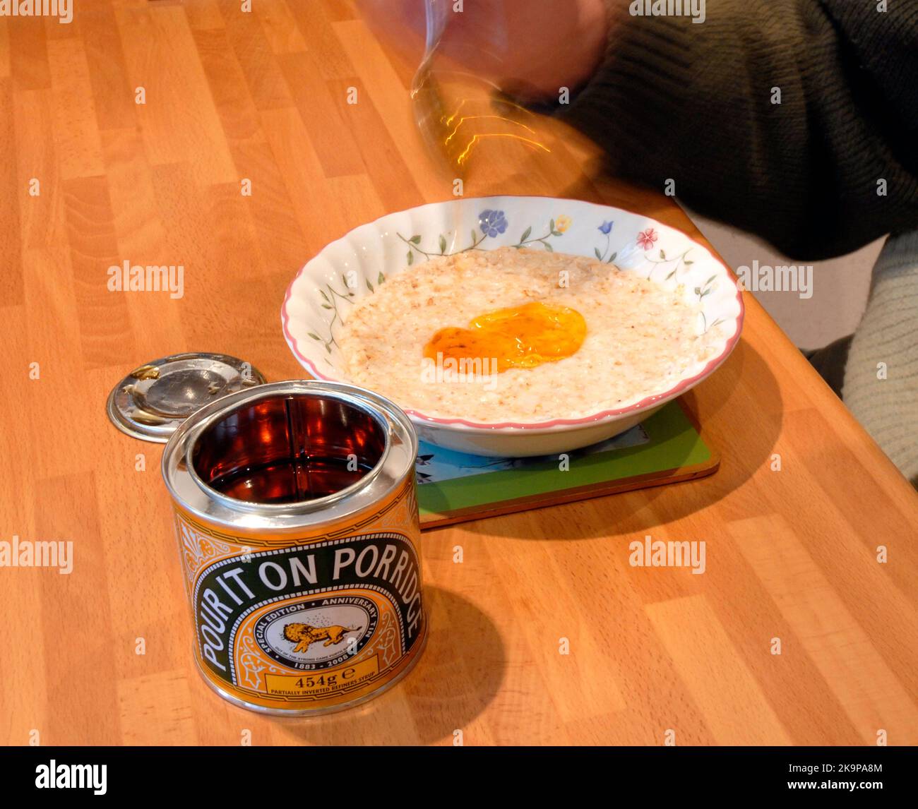 Dish of porridge, with tin of golden syrup, with syrup being put on the ...