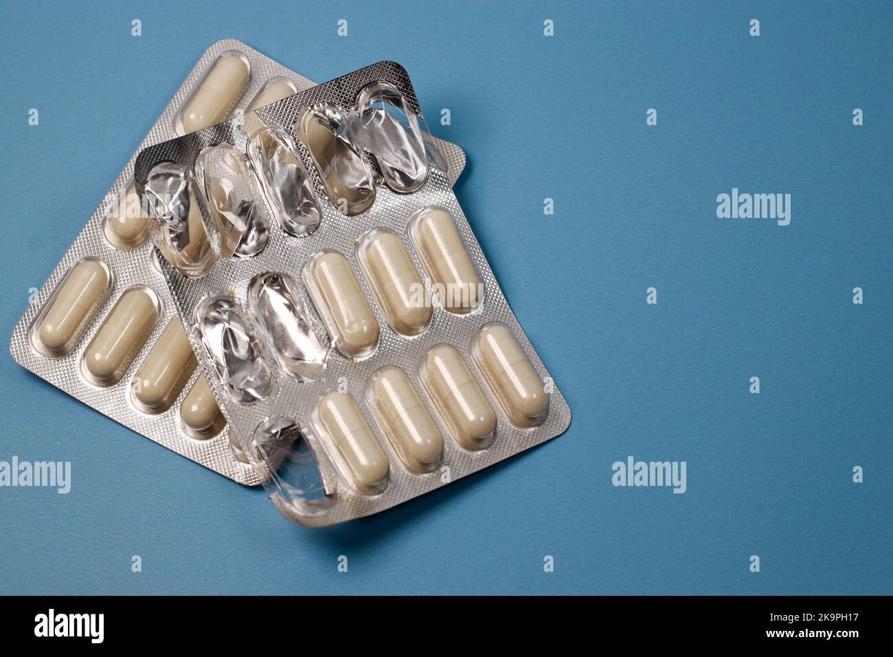 white capsules and pill pack on blue background Stock Photo - Alamy