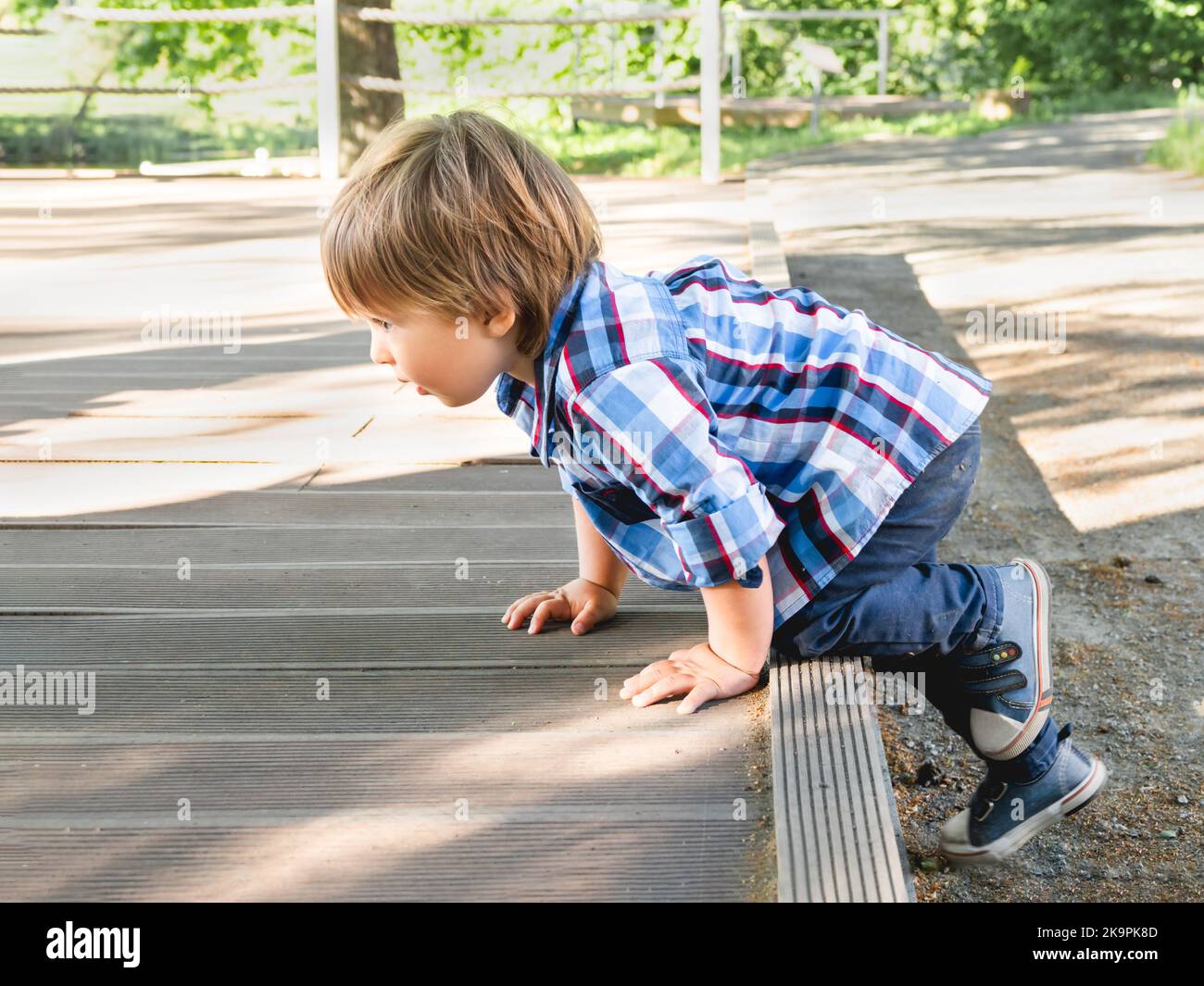 Curious toddler is climbing upstairs in recreation park. Leisure ...
