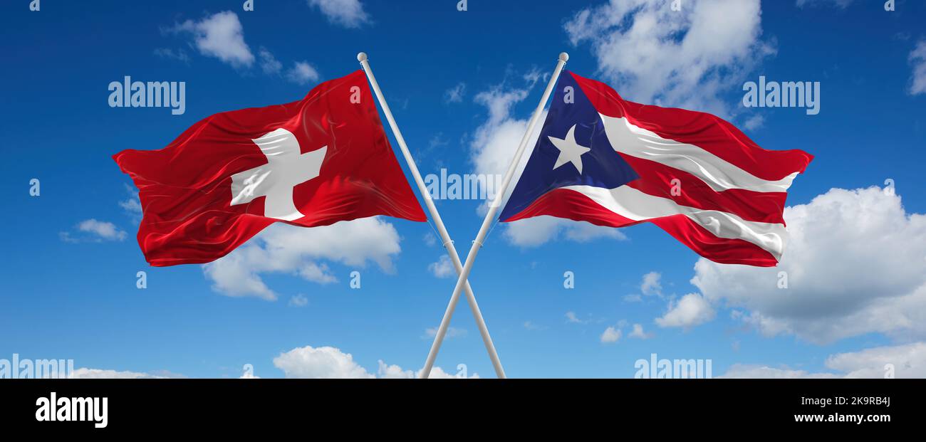 two crossed flags Puerto Rico and Switzerland waving in wind at cloudy sky. Concept of ...