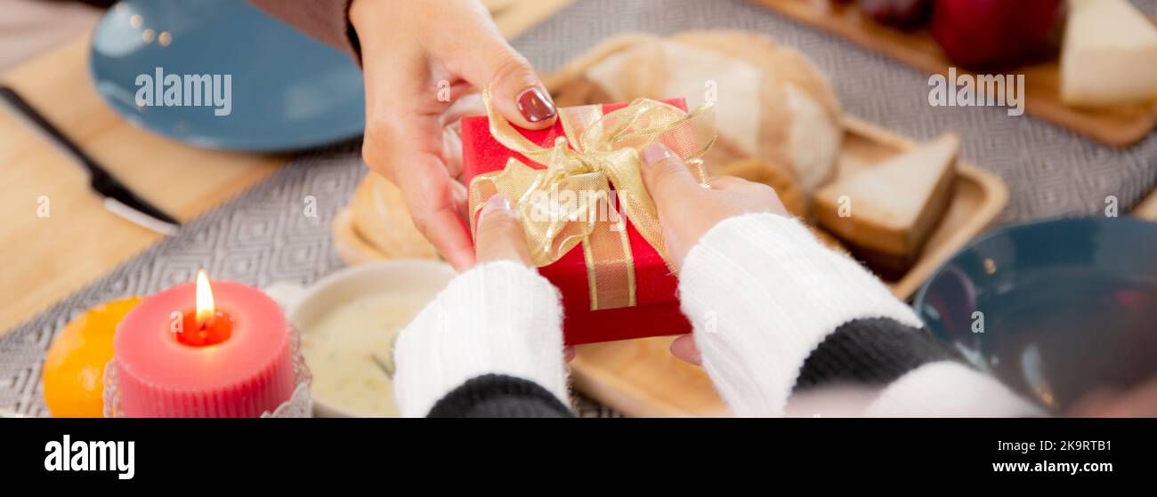 Happy family with daughter giving gift box with mother during dinner at ...