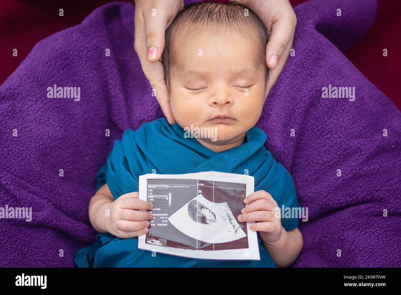 newborn baby holding ultrasound copy in hand and sleeping at mother ...