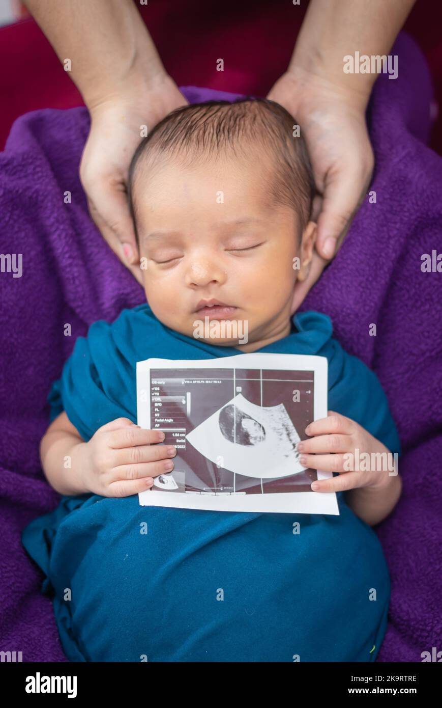 newborn baby holding ultrasound copy in hand and sleeping at mother ...