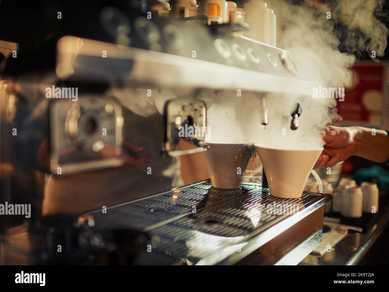 Nice and steamy. an unrecognizable person cleaning two coffee cups ...