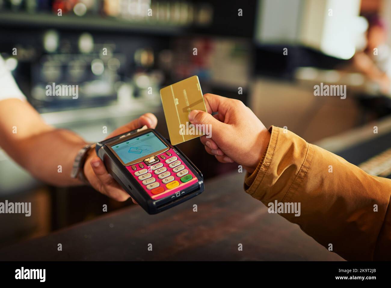 Come back soon. Closeup of an unrecognizable person paying their bill with a card machine inside ...