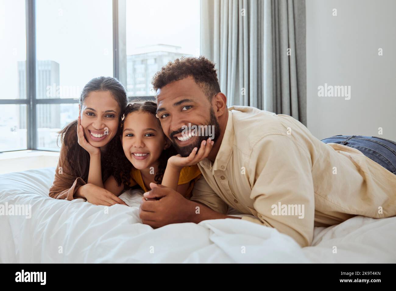 Family, hug and smile, parents and child lying on bed in portrait, love ...