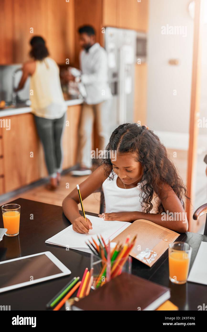 Getting her homework done before dinner. a little girl doing her ...