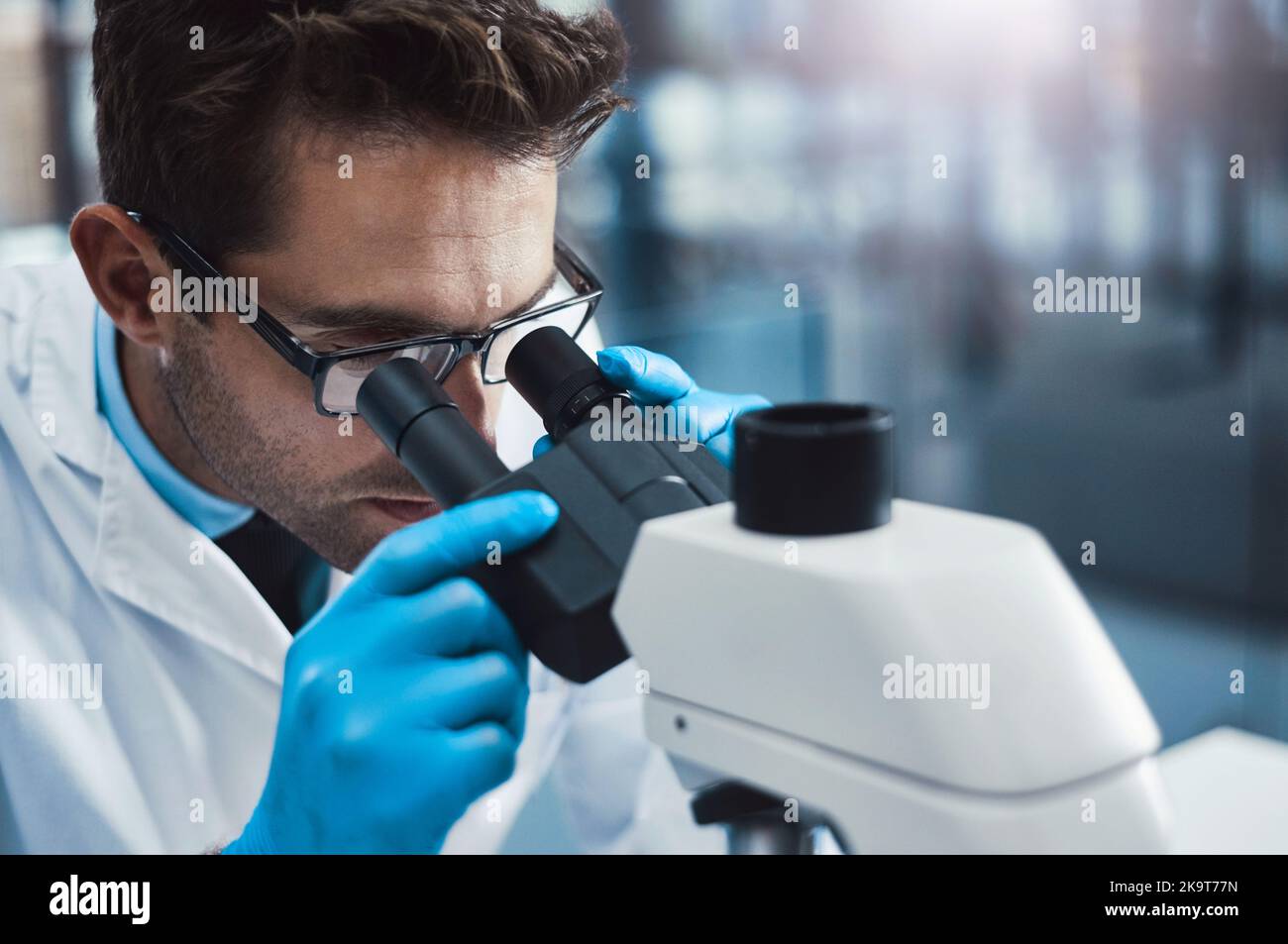 Taking a closer look. a young male scientist working in a lab with a ...