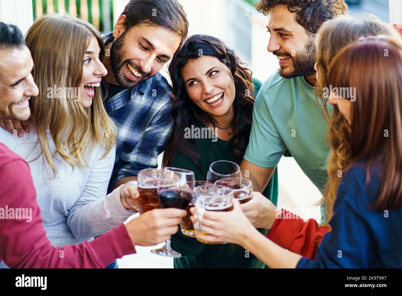 Friends cheering together toasting beer and wine standing on the ...