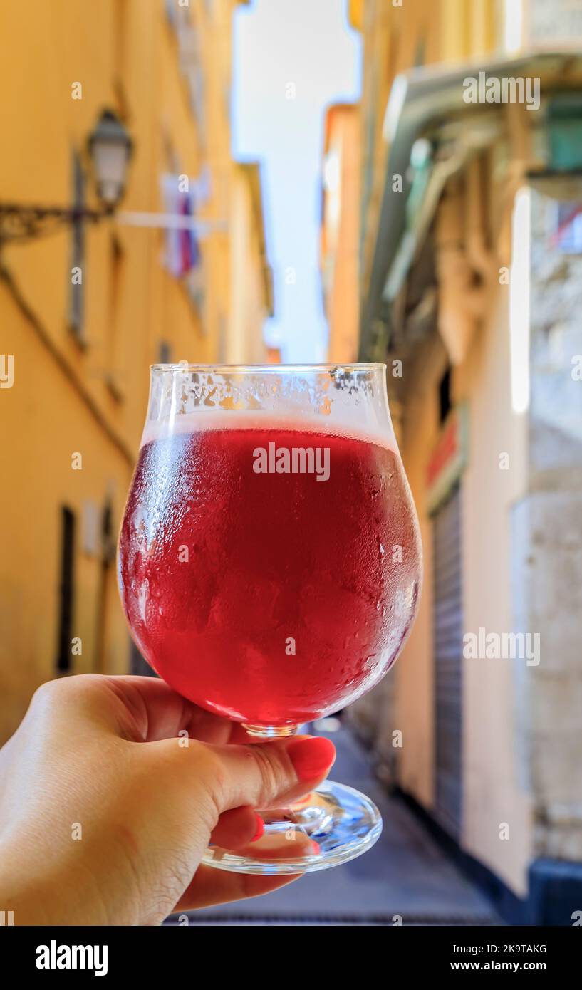 Glass of a raspberry Lambic ale at an outdoor restaurant with a ...