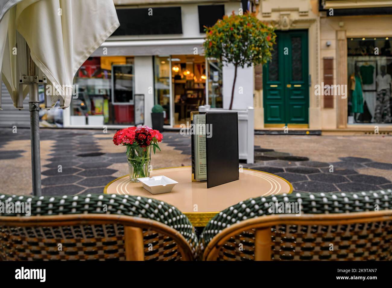 An outdoor table with flowers at a bakery cafe with buildings in old ...