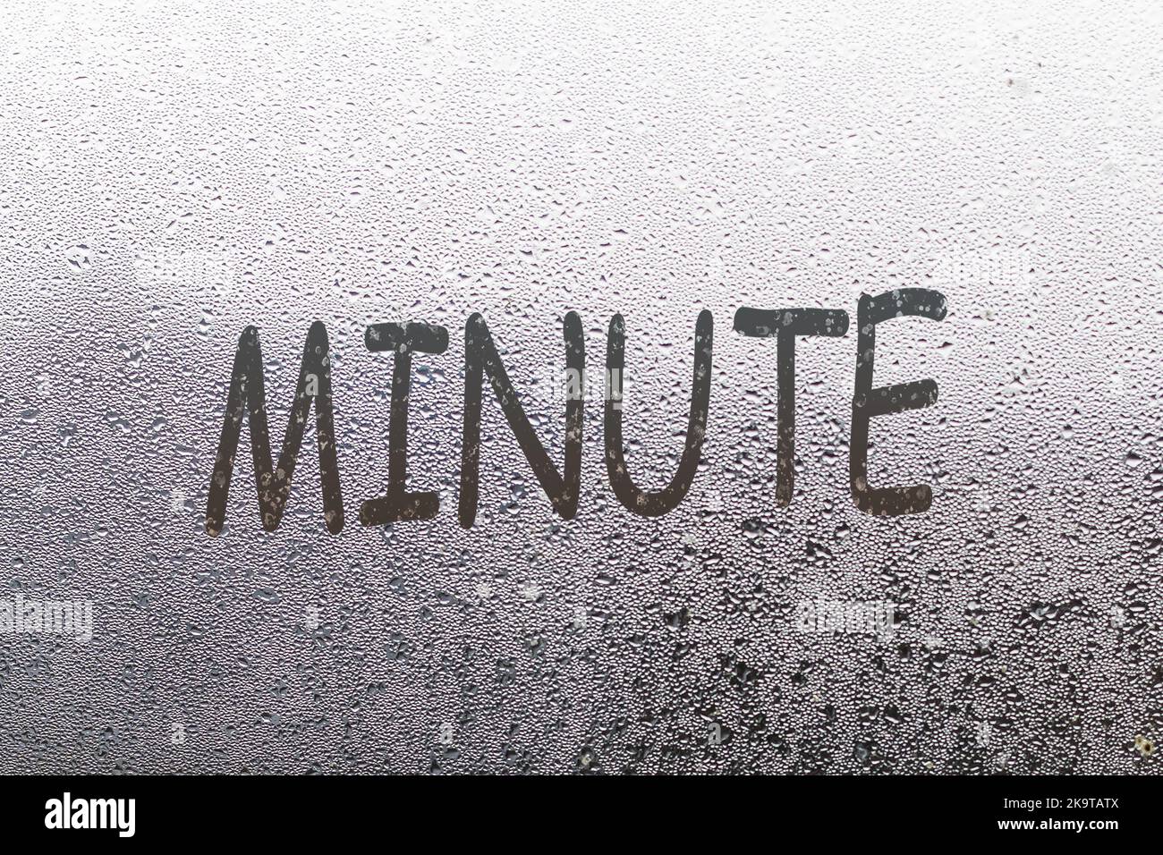 the word minute handwritten on night wet window glass Stock Photo - Alamy