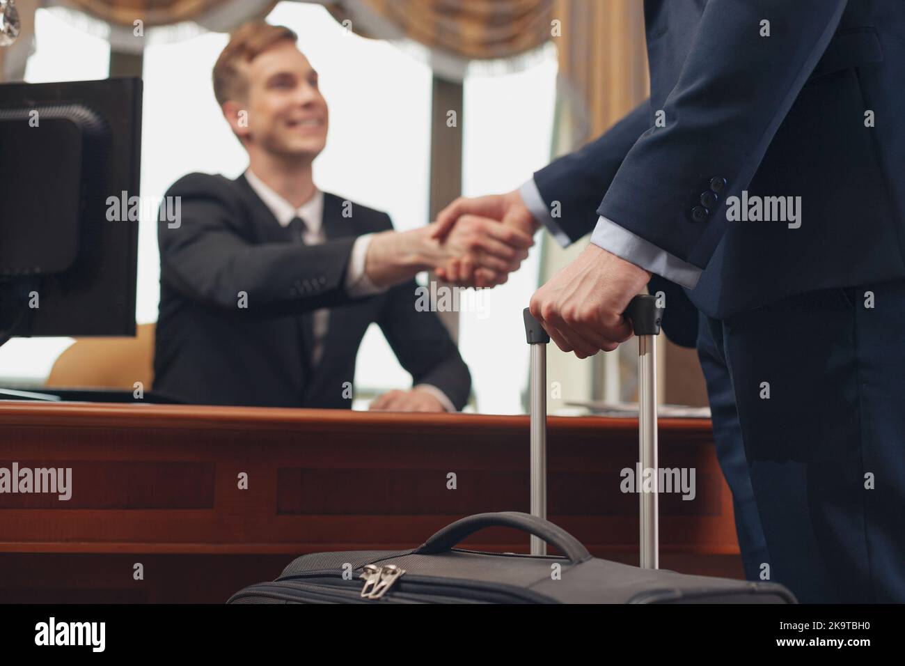 Close up photo of receptionist and client in expensive hotel shaking ...