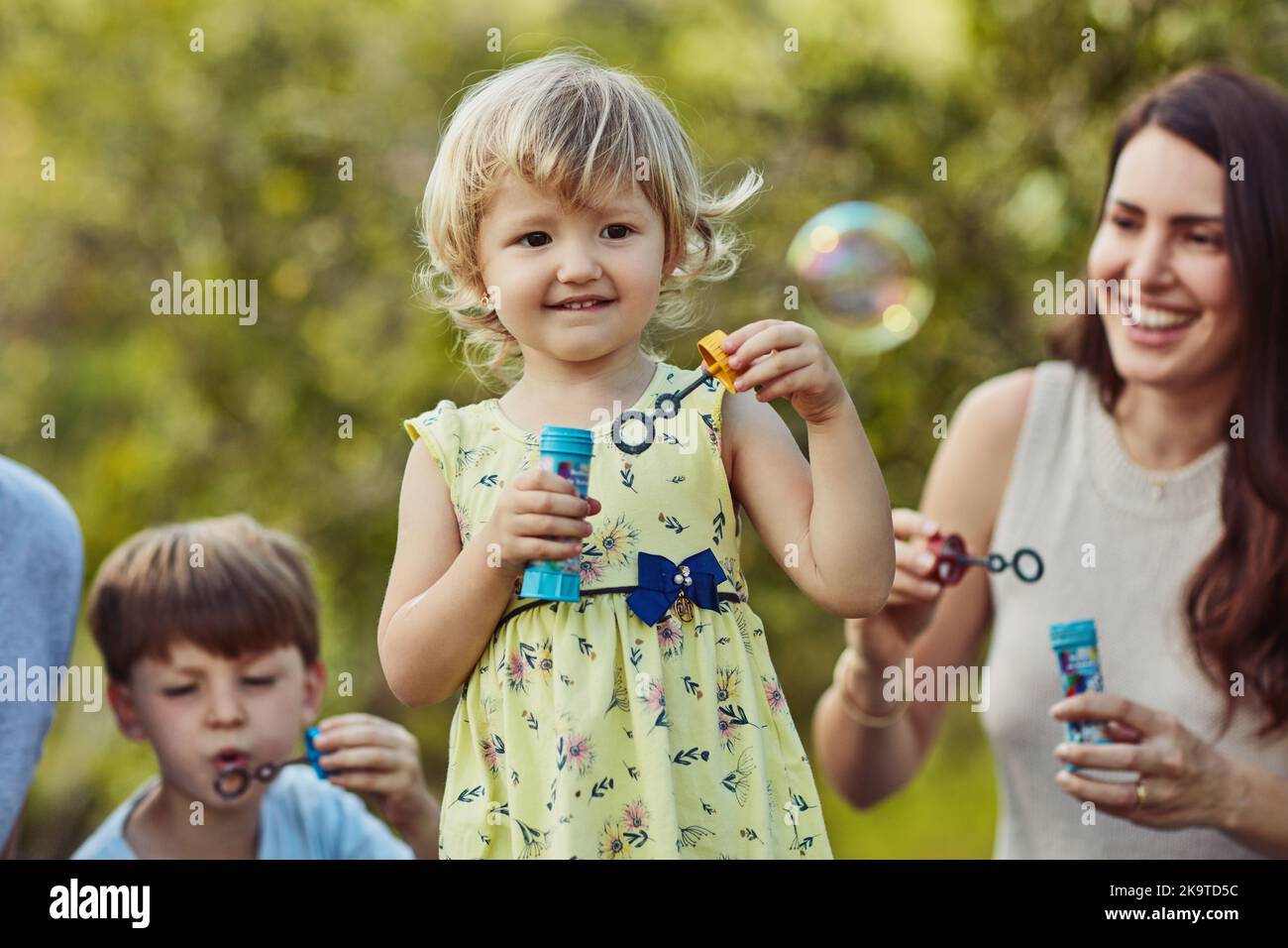 Out for some bubble fun. an adorable little girl blowing bubbles with ...